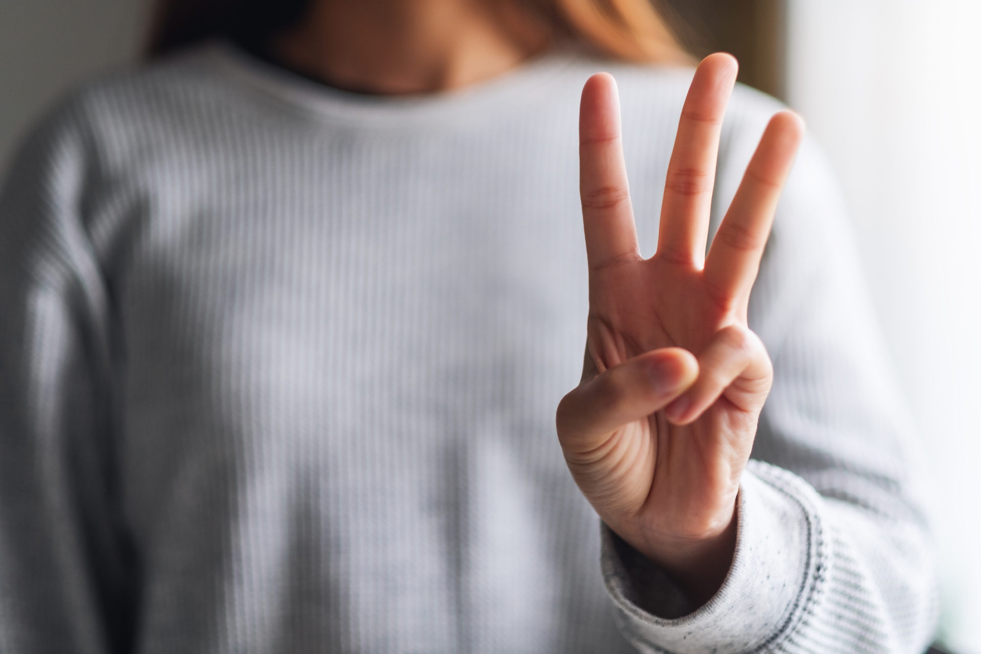 a woman making and showing number three hand sign | PAAS National