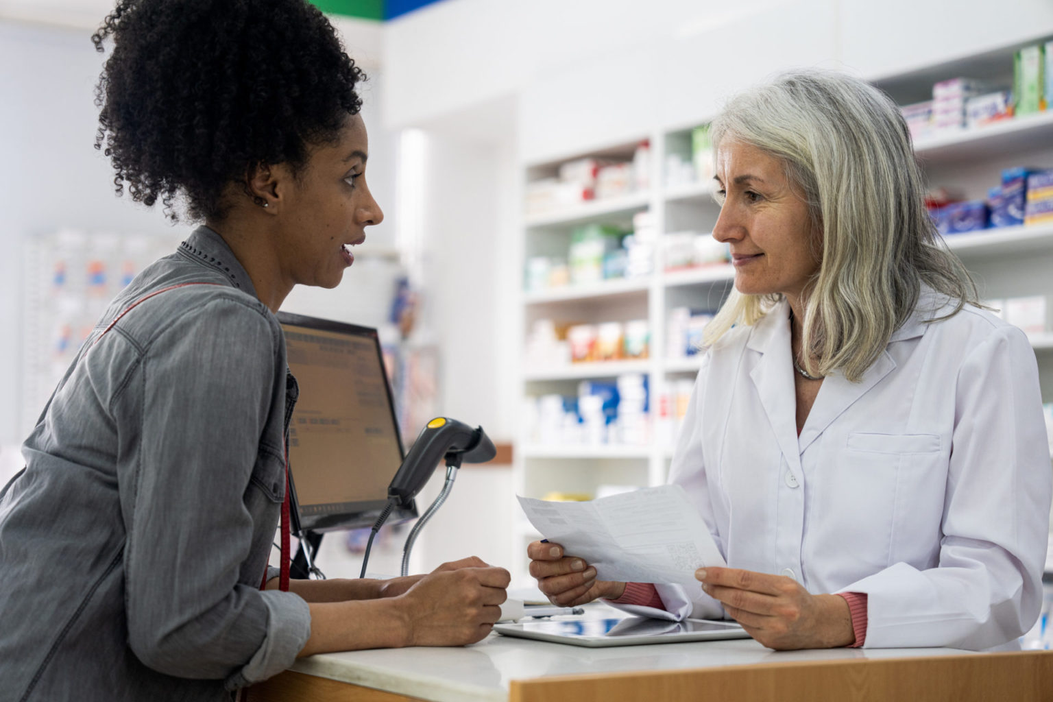 Mature female pharmacist taking an African-American woman’s ...